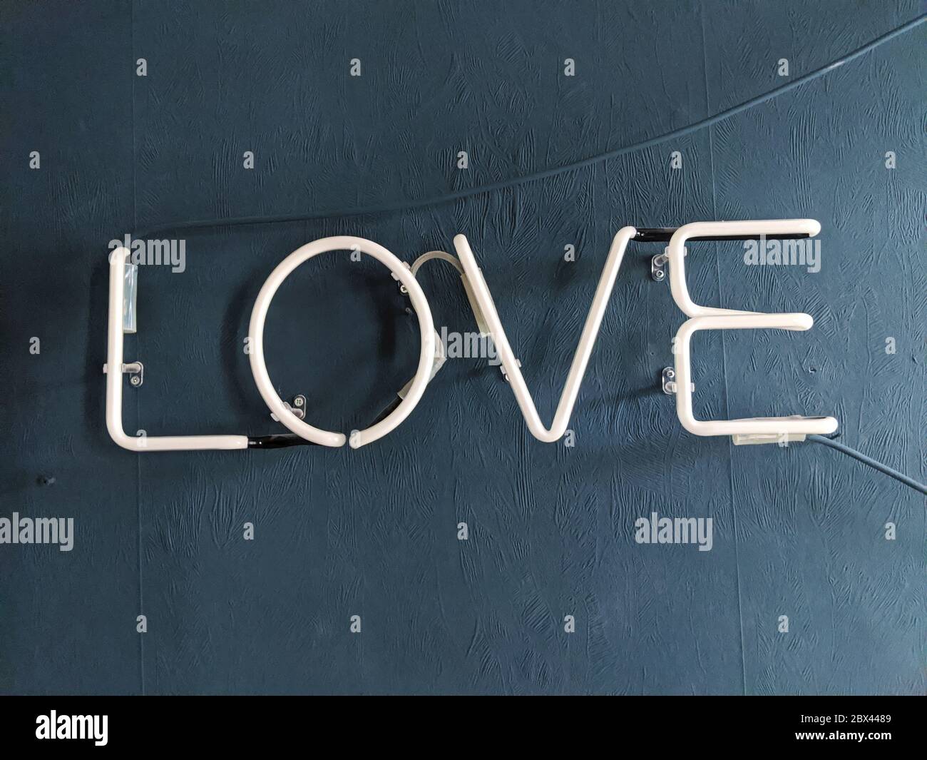 Neon light love sign on dark grey blue background Stock Photo - Alamy