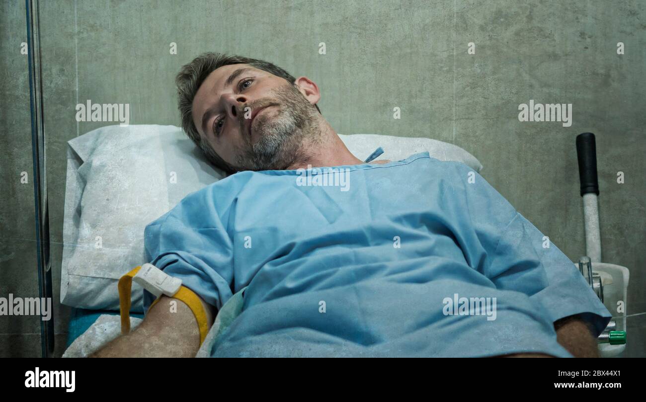 dramatic portrait of attractive worried and ill man in patient gown ...