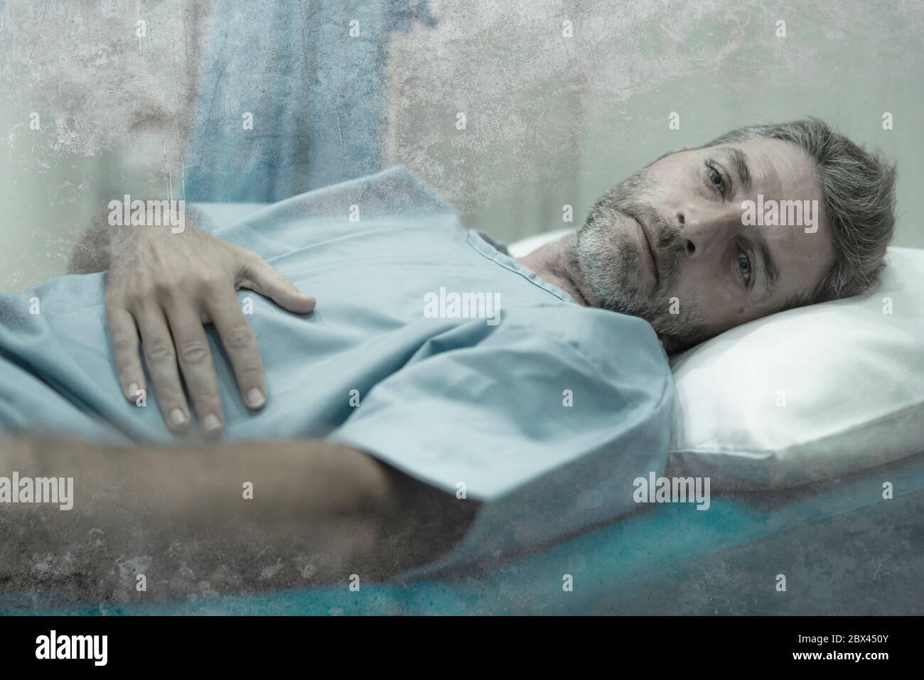 dramatic portrait of attractive worried and ill man in patient gown ...