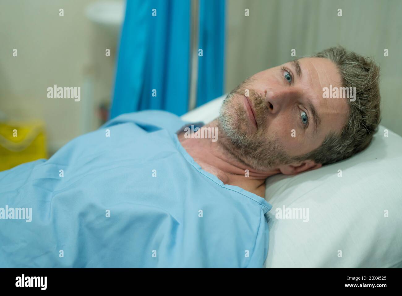 dramatic portrait of attractive worried and ill man in patient gown ...