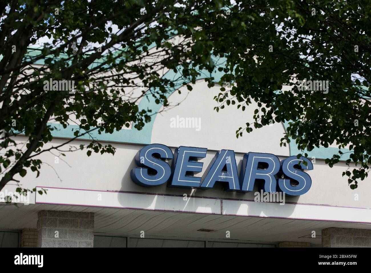A logo sign outside of a Sears Hometown retail store location in ...