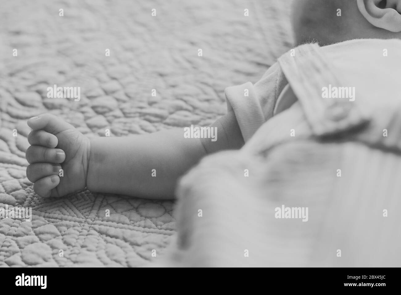 Baby lying on back on bed indoors with arm wresting to his side in ...