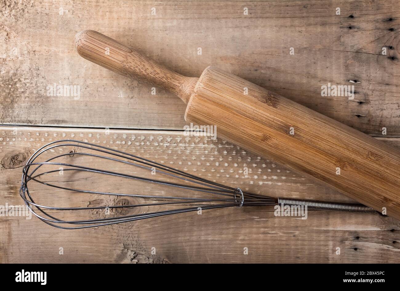 Top view of whisk and rolling pin baking utensils on wooden background ...