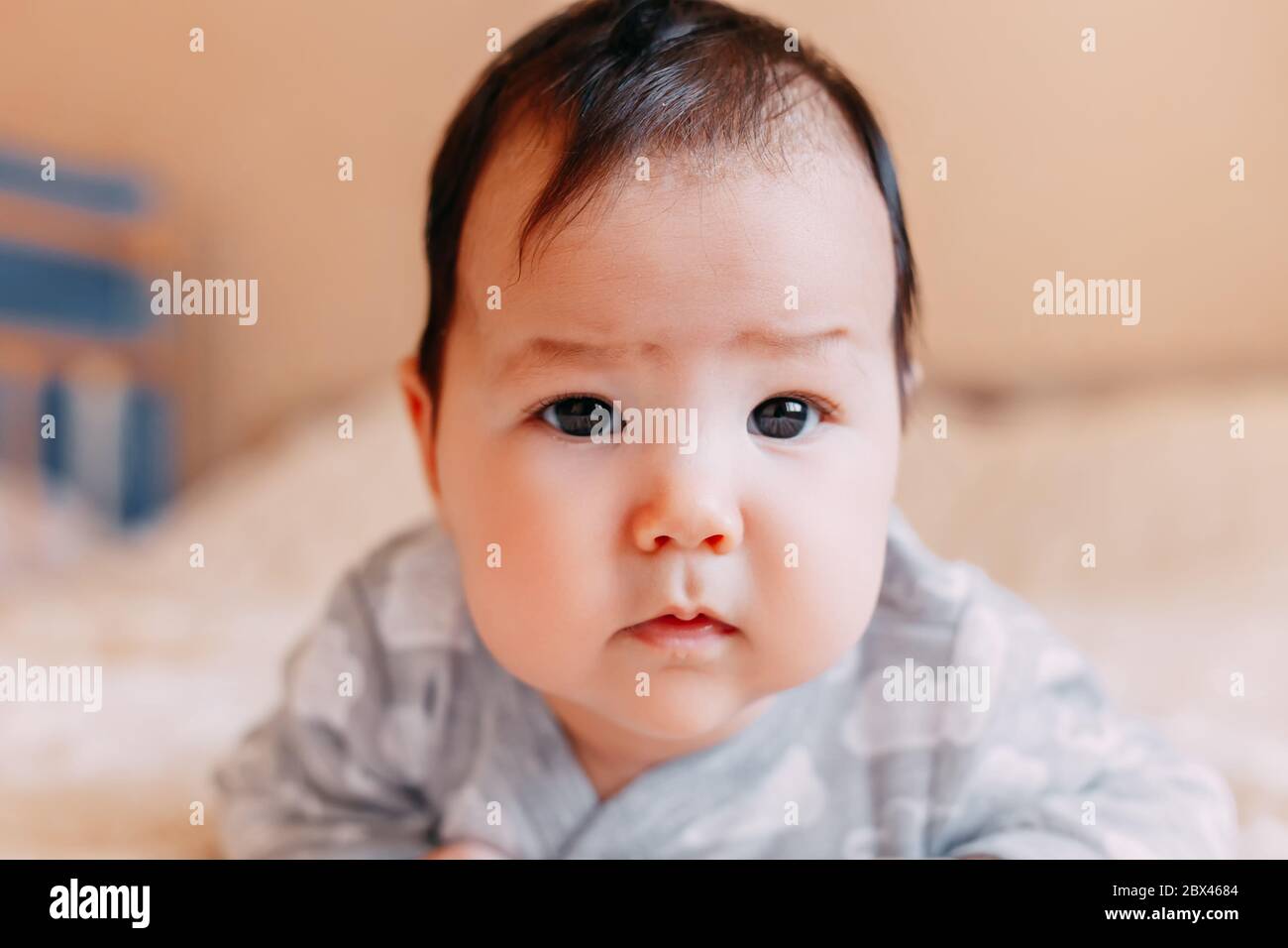 Baby girl on her stomach. Looking up with surprised expression Stock ...