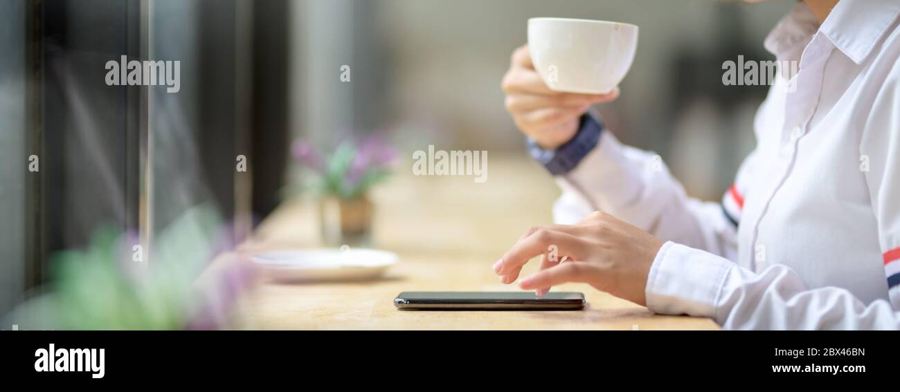 Side view of female university student relaxing with smartphone and ...