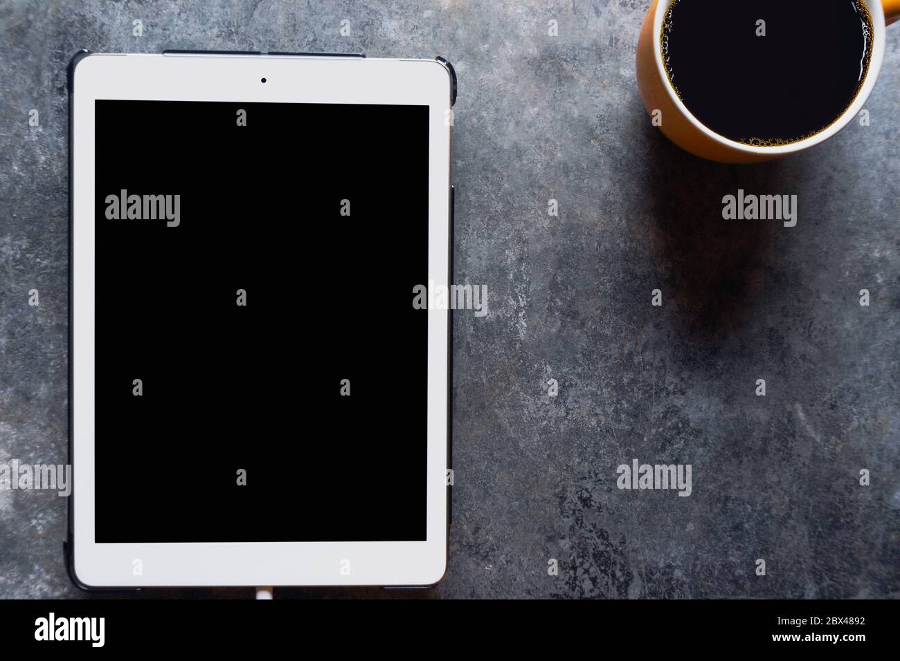 Coffee break. Top view yellow cup of coffee with tablet on a table ...