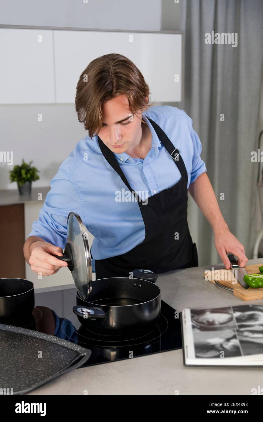 Handsome young man checking a pot at a kitchen on an out of focus ...