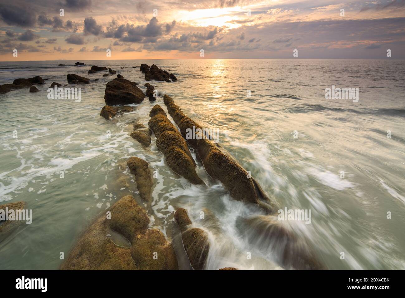 Amazing twilight Sunset seascape with sea wave hitting the green moss ...