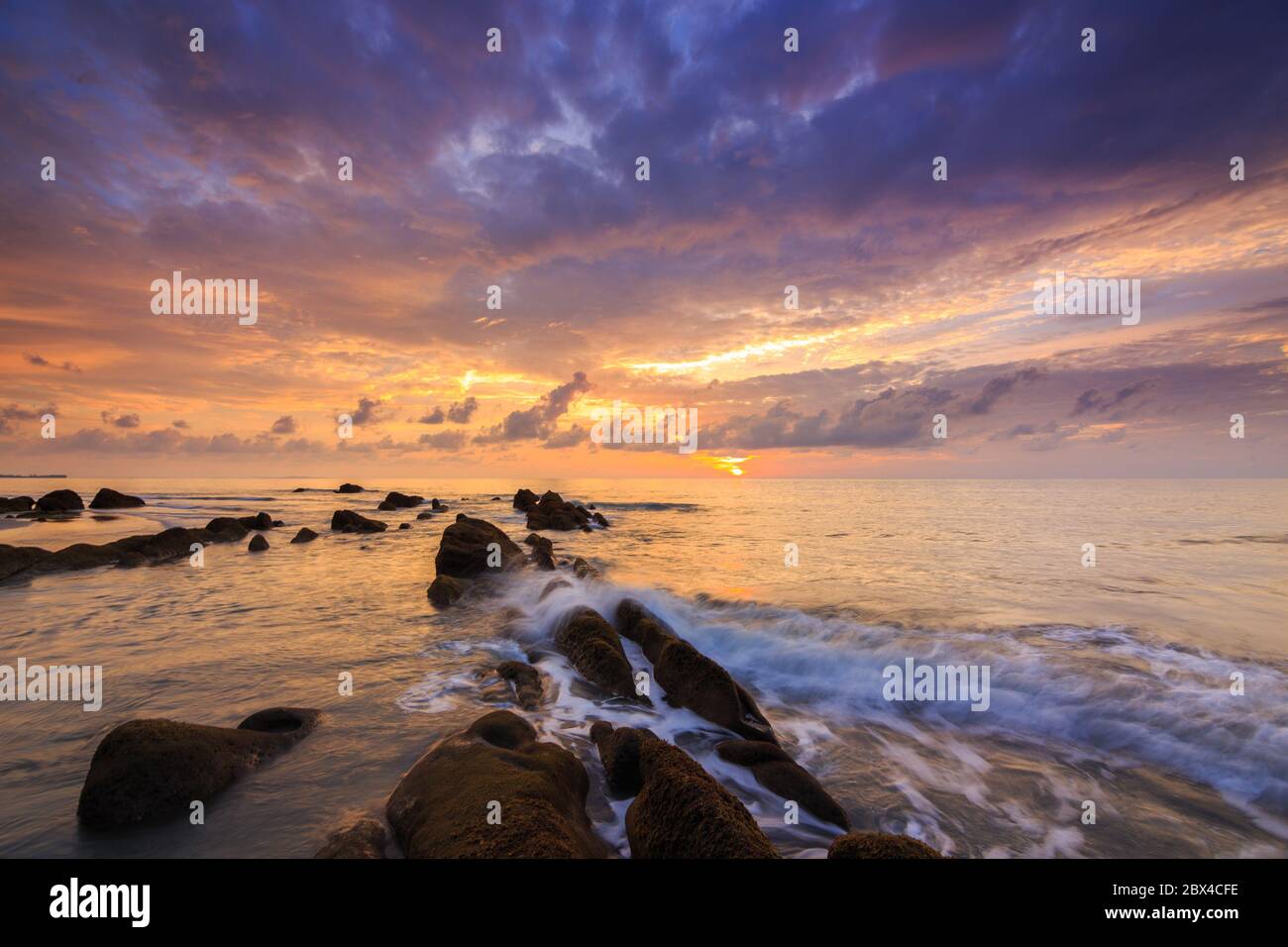 Amazing twilight Sunset seascape with sea wave hitting the green moss ...