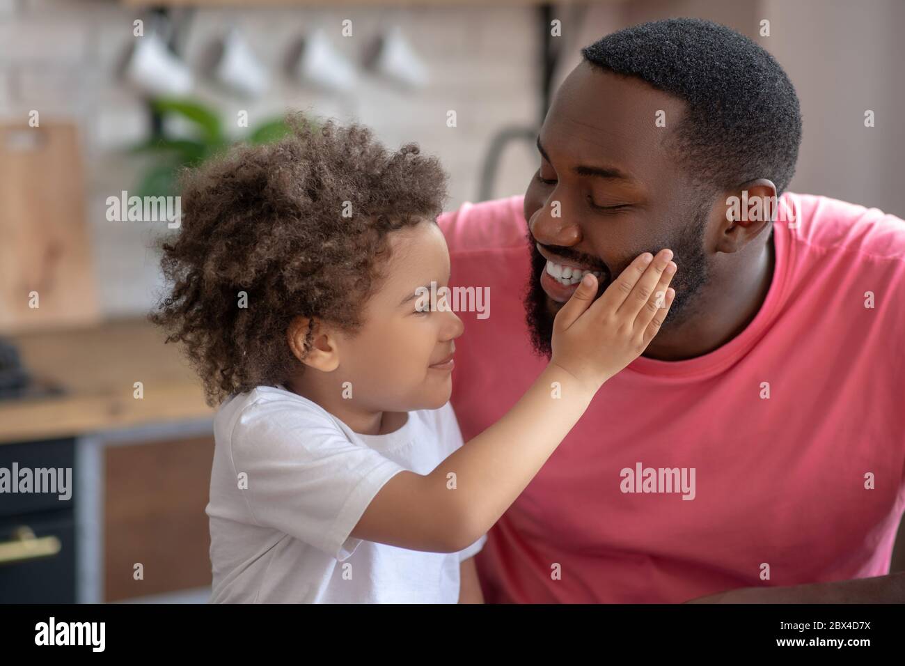 Sweet little girl touching her fathers face and looking pleased Stock ...