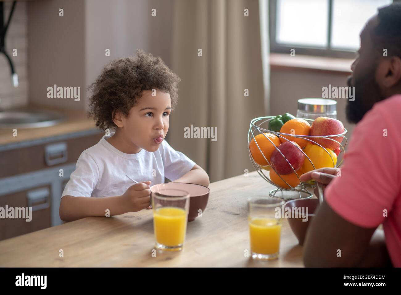 Cute little kid showing tongue to her father not wanting to eat Stock ...
