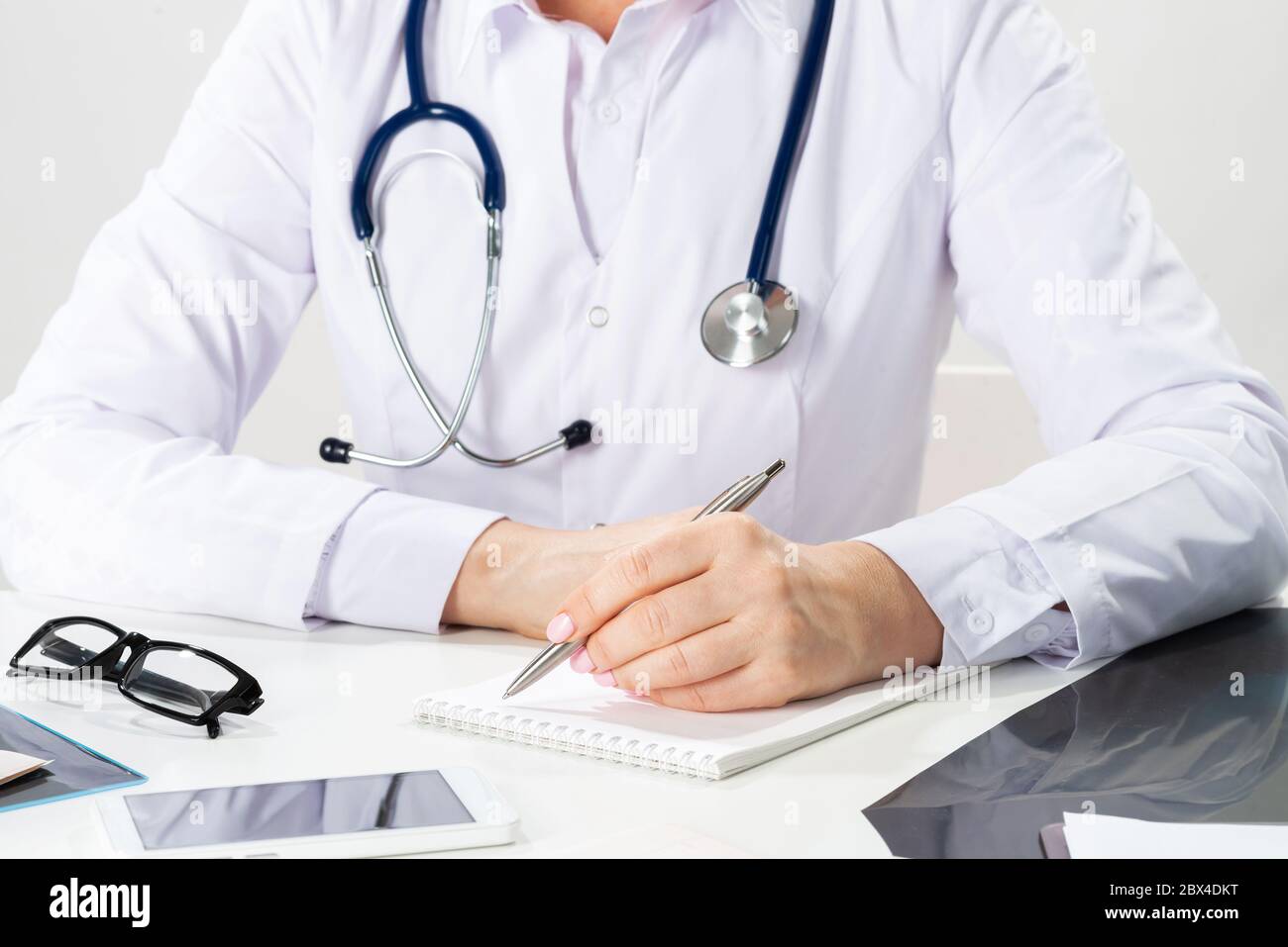 Close up female doctor hands writing on paper Stock Photo - Alamy
