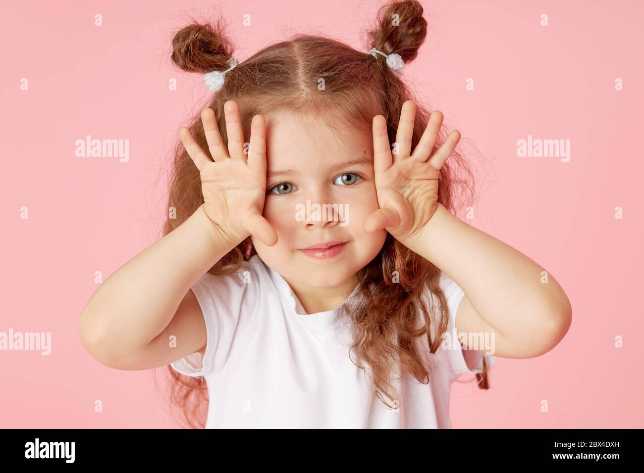 Portrait of surprised cute little toddler girl child over pink ...