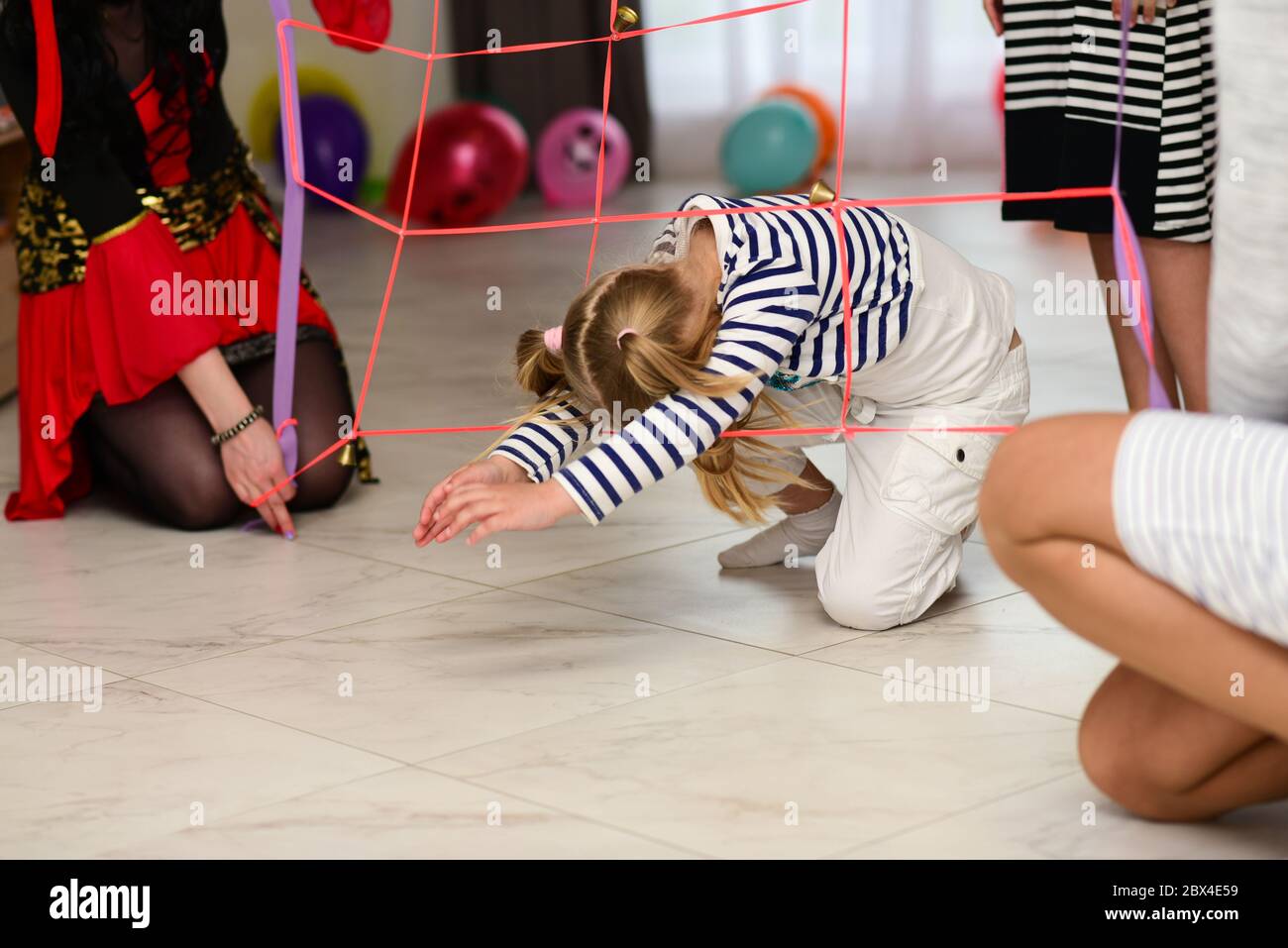 Children at a party play a game to climb through a rope with a bell ...