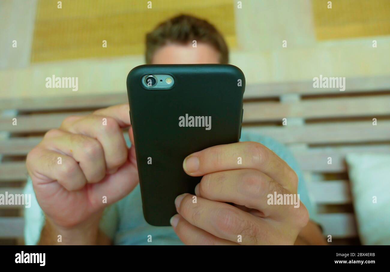 close up hands holding mobile phone of young man at home bedroom using ...