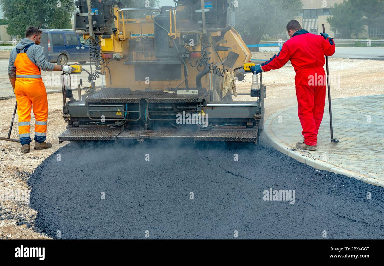 Worker regulate tracked paver laying asphalt heated to temperatures ...