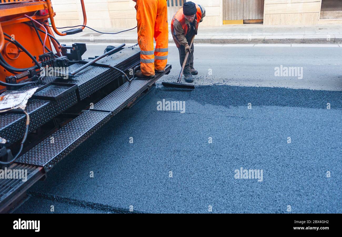 Worker regulate tracked paver laying asphalt heated to temperatures ...