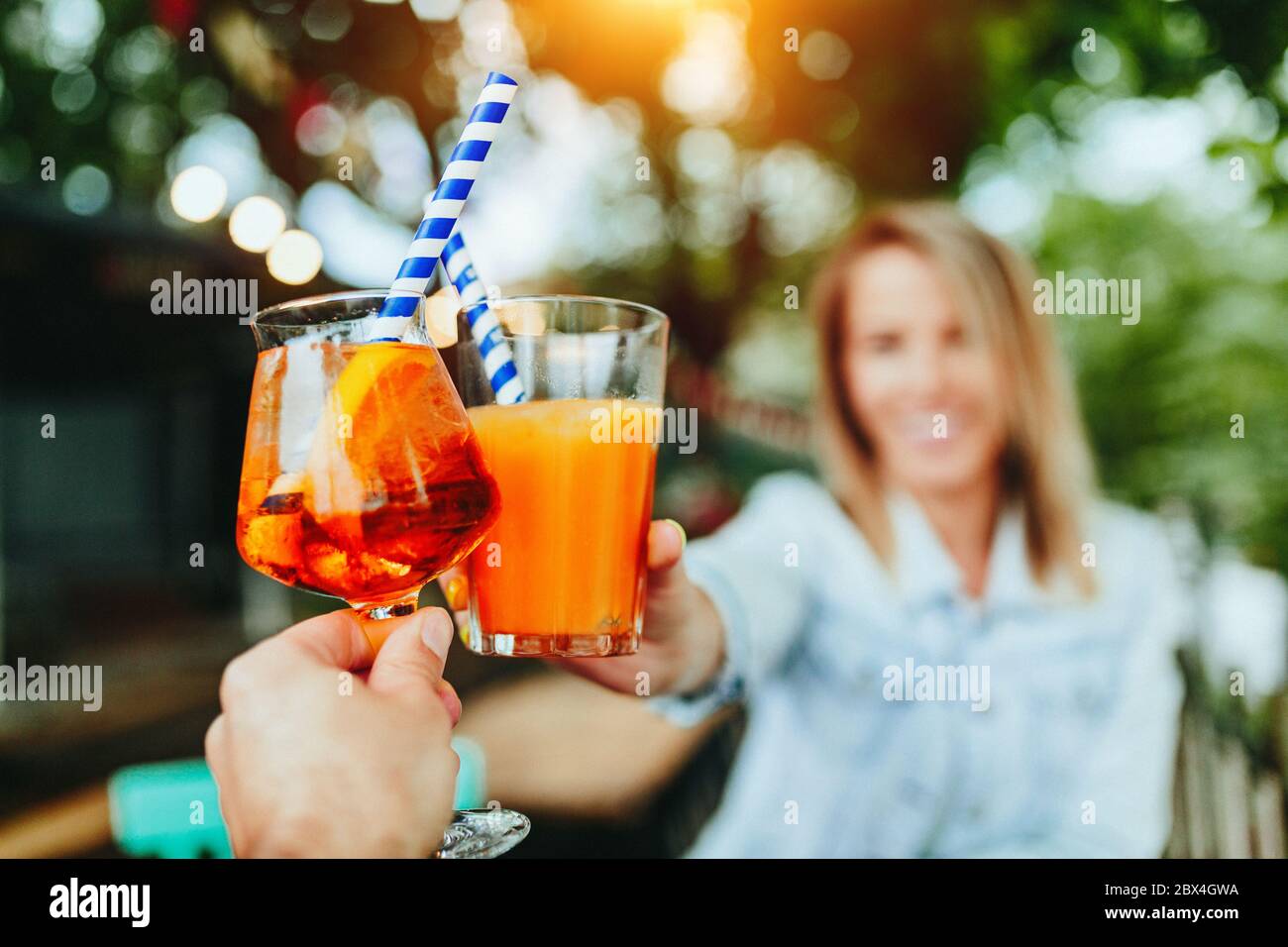 Celebrating life. Toast with aperol spritz. Young smiling woman in ...