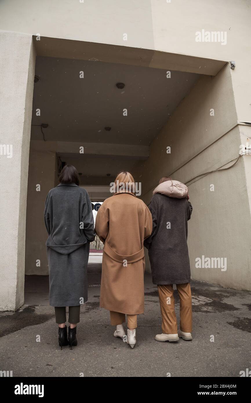 Back view of three models wearing warm woolen coats posing in city ...