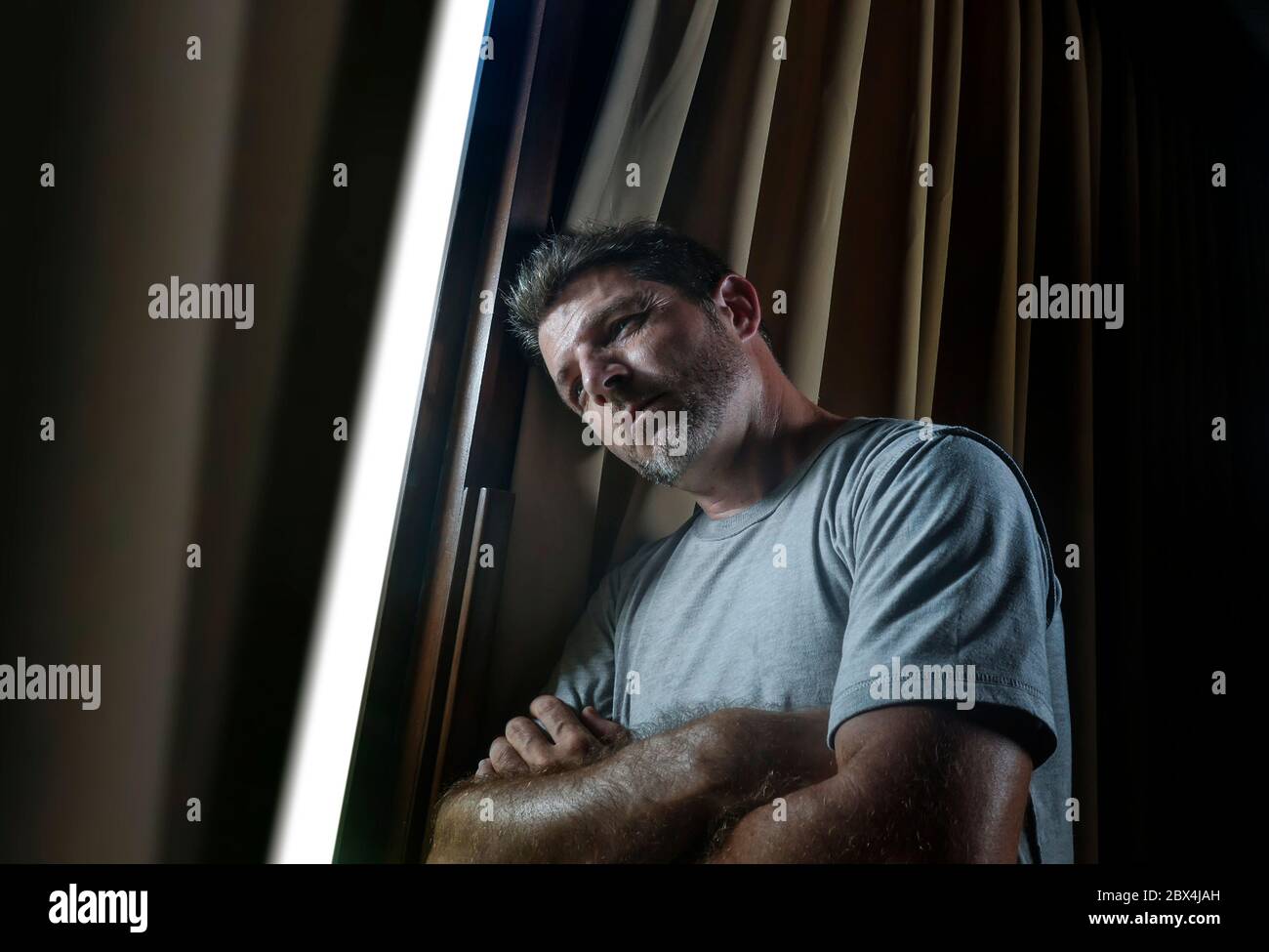 dramatic light indoors portrait of young sad and depressed attractive ...