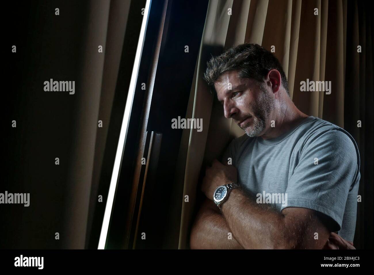 dramatic light indoors portrait of young sad and depressed attractive ...