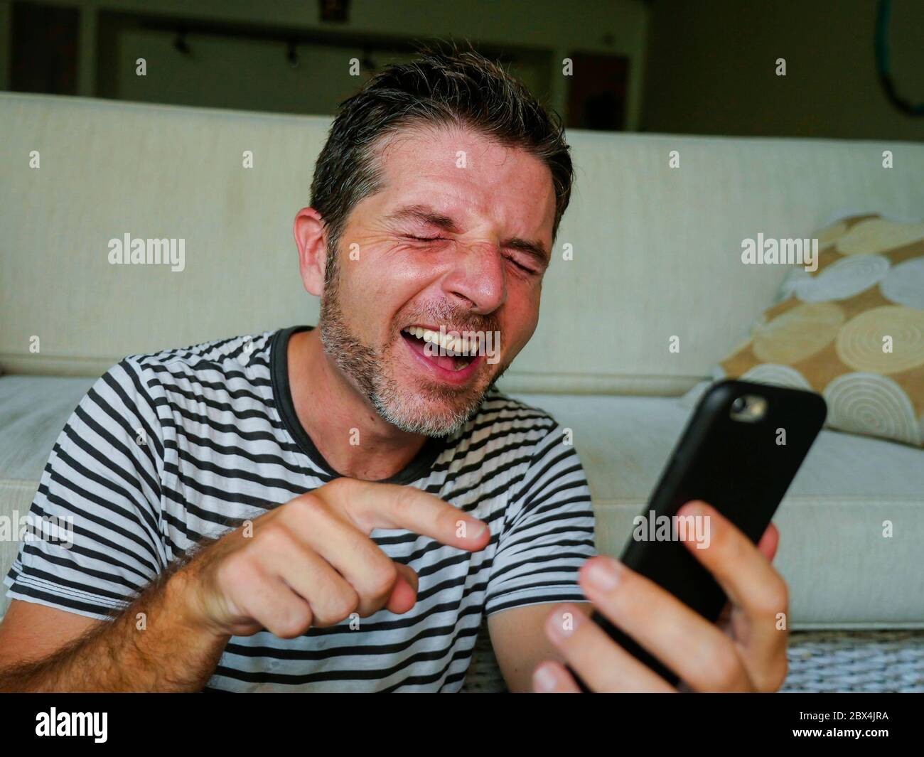 lifestyle home portrait of young happy man laughing like crazy using ...