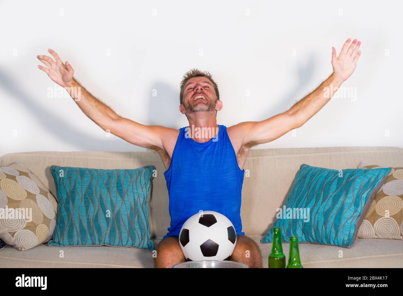 young attractive man happy and excited watching football match on TV ...