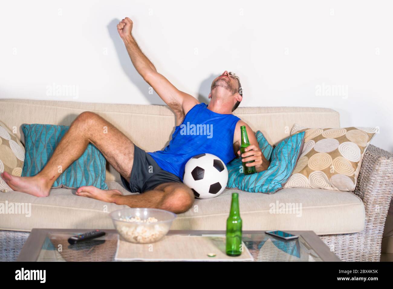 young attractive man happy and excited watching football match on TV ...