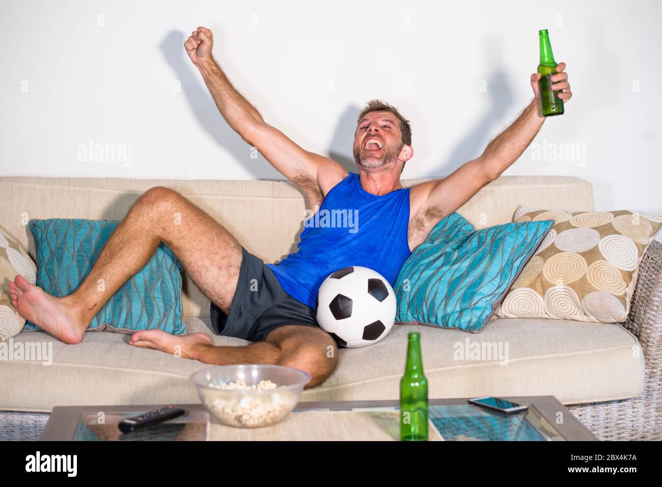 young attractive man happy and excited watching football match on TV ...