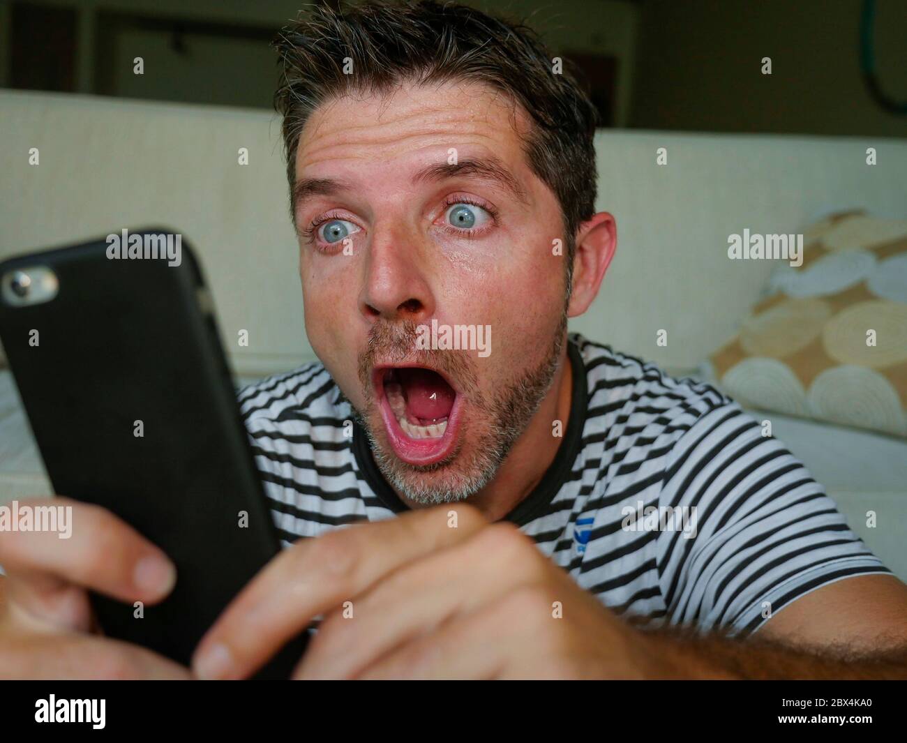 young perplexed and shocked man using mobile phone looking internet ...