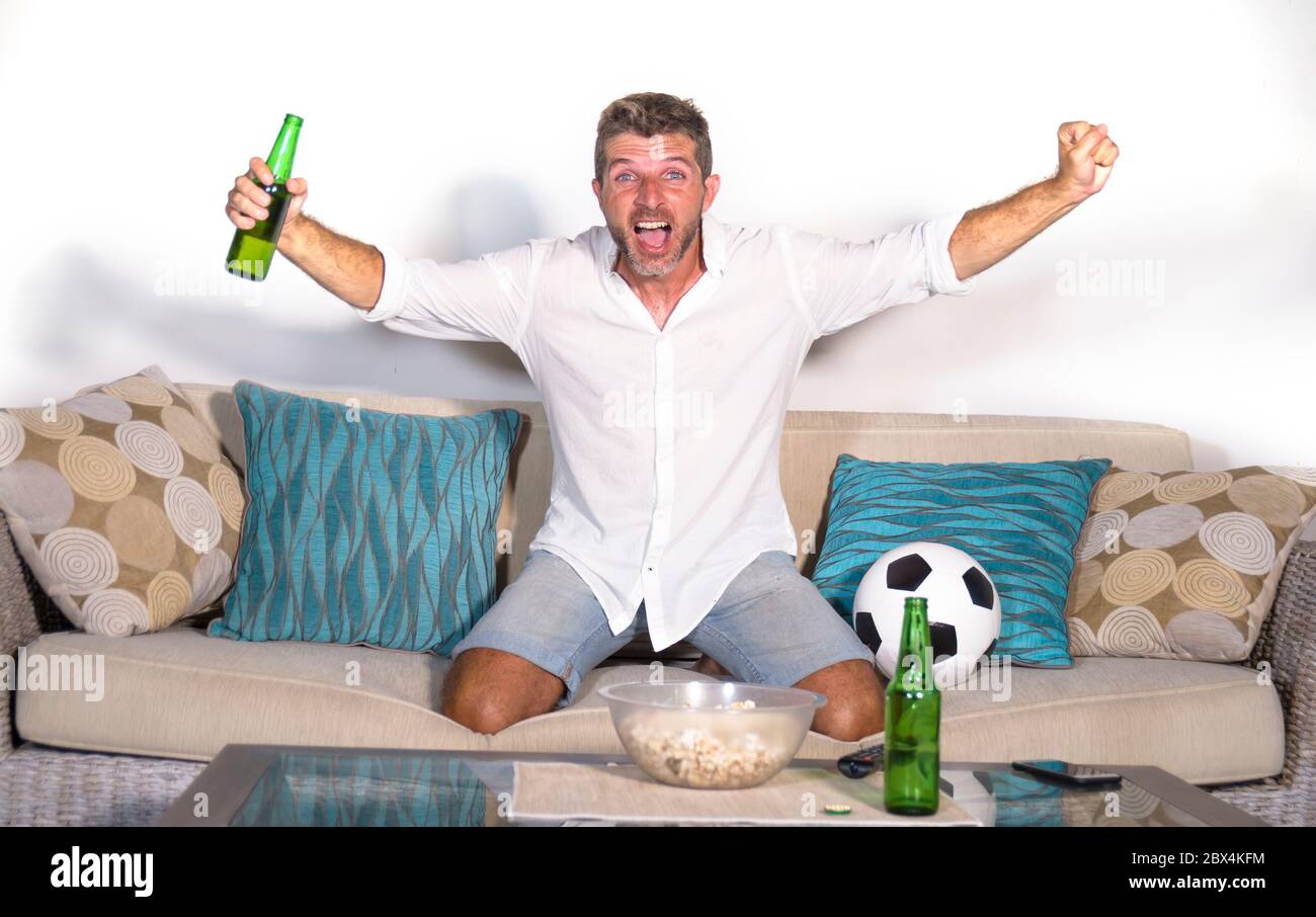 young attractive man happy and excited watching football match on TV ...