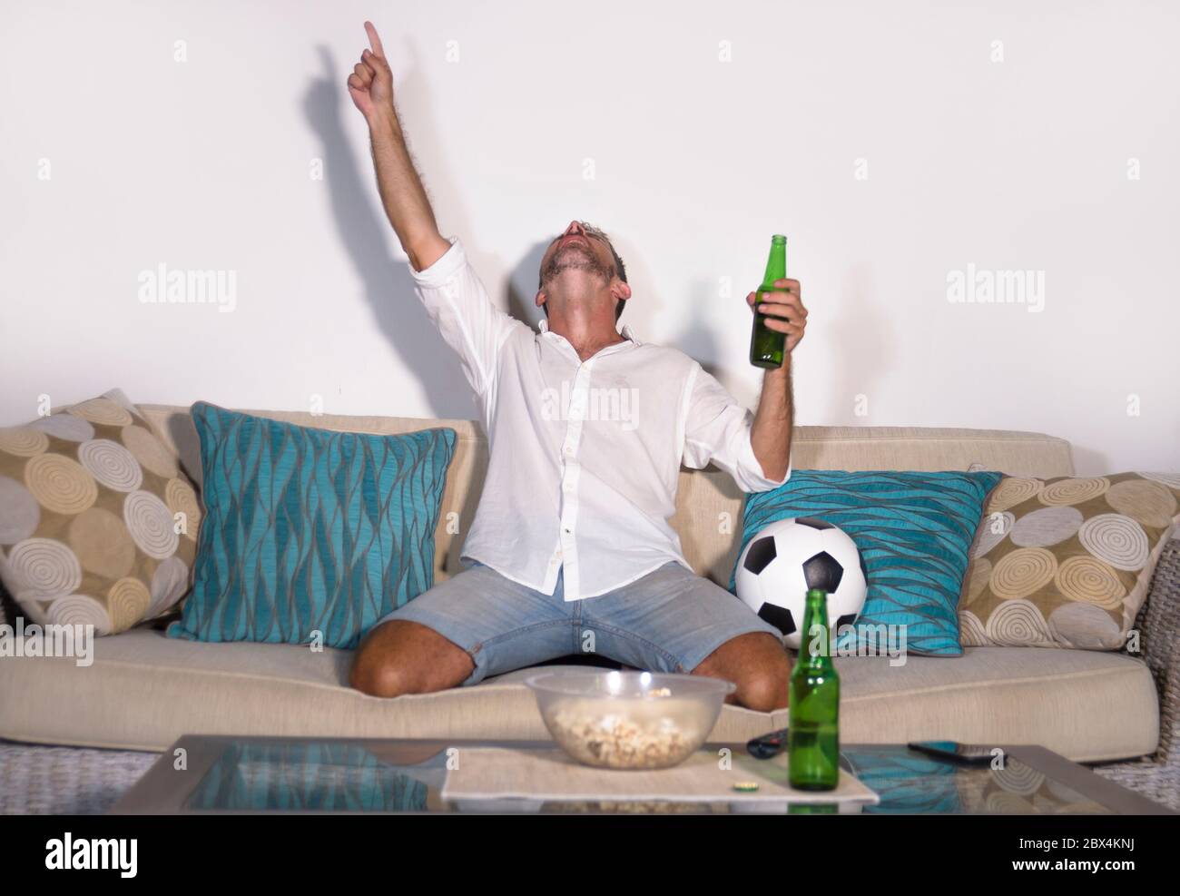 young attractive man happy and excited watching football match on TV ...