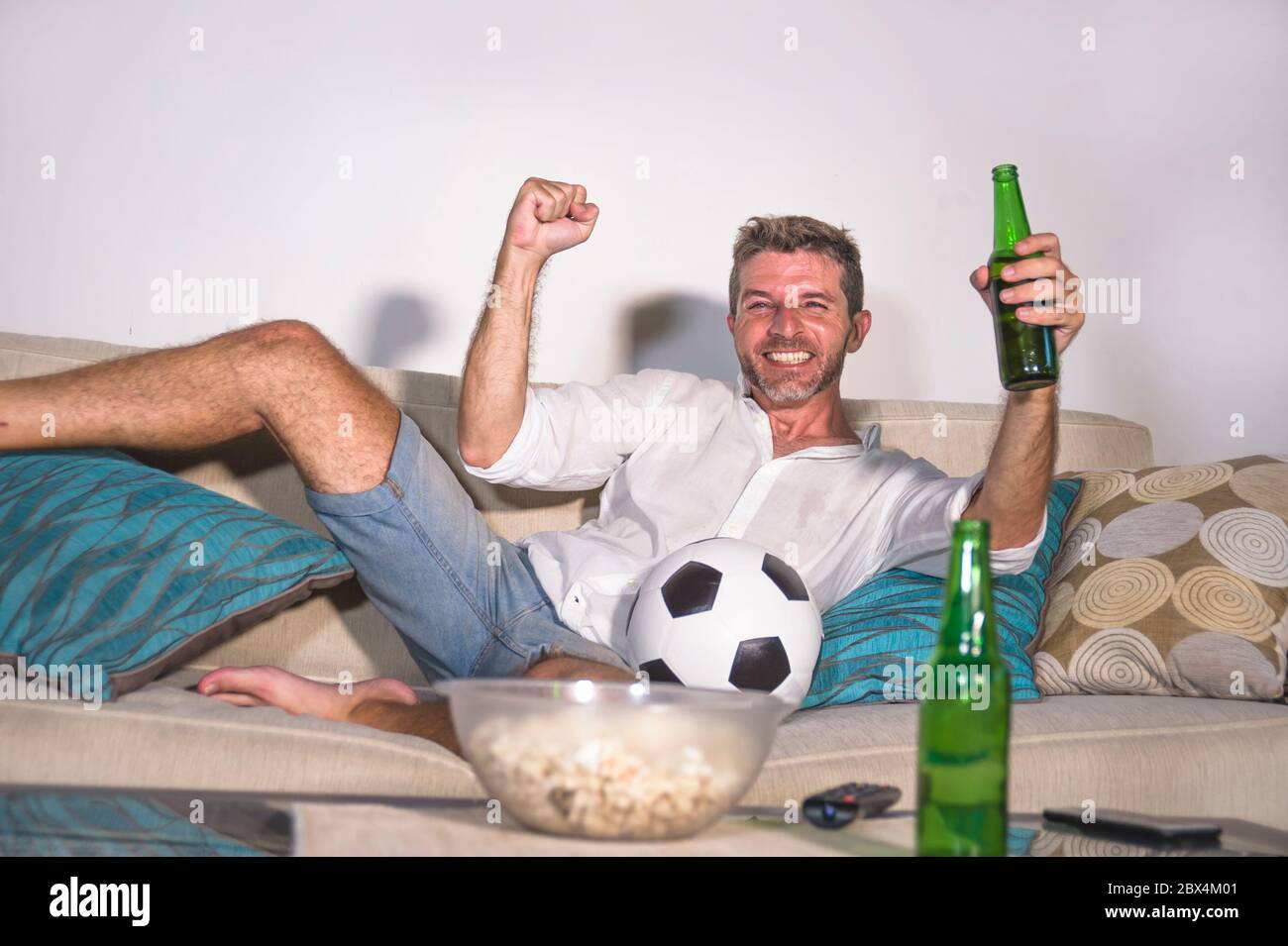 young attractive man happy and excited watching football match on TV ...