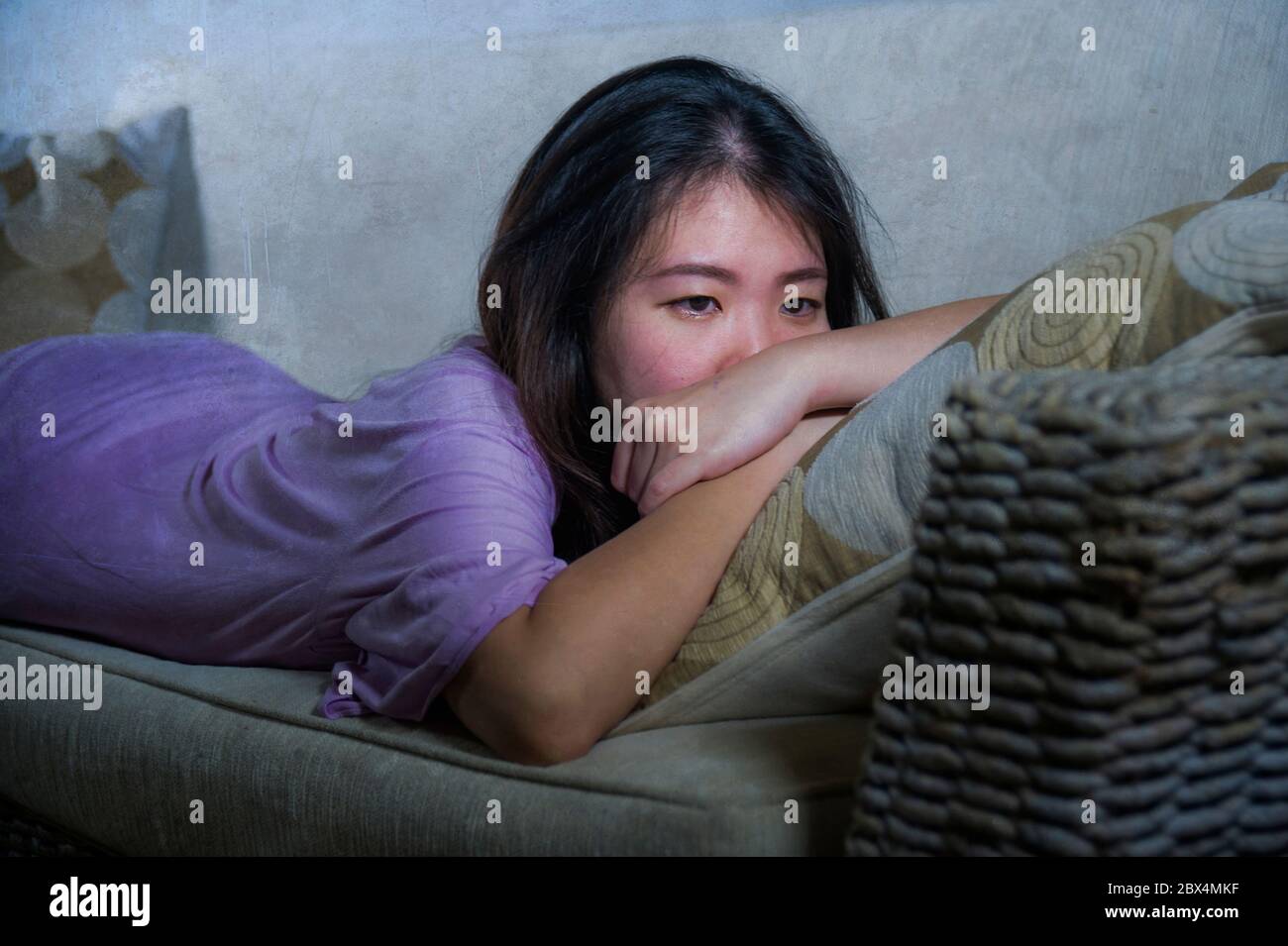 lifestyle home couch portrait of young sad and depressed Asian Chinese ...