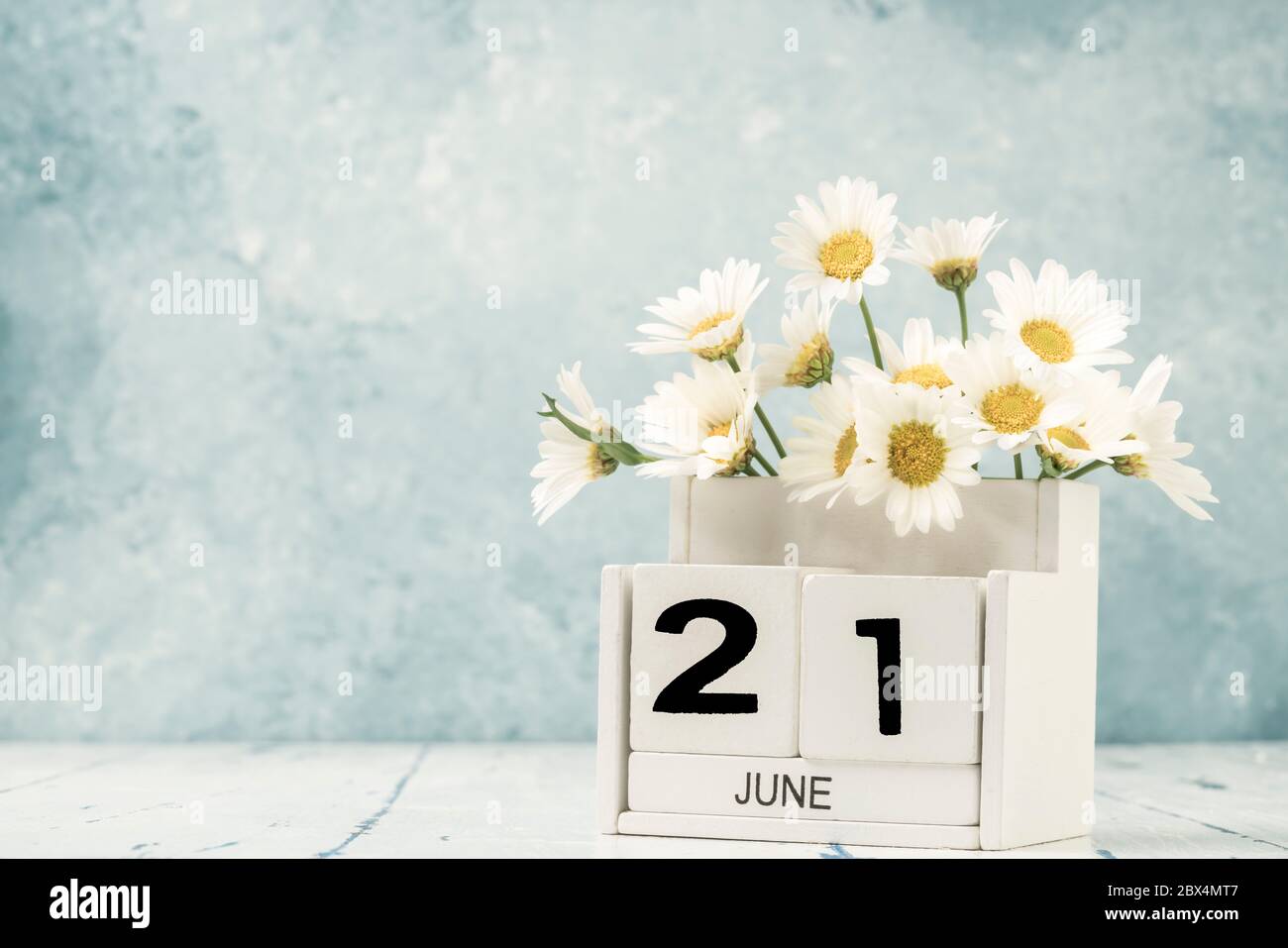 White cube calendar for june decorated with daisy flowers over blue ...