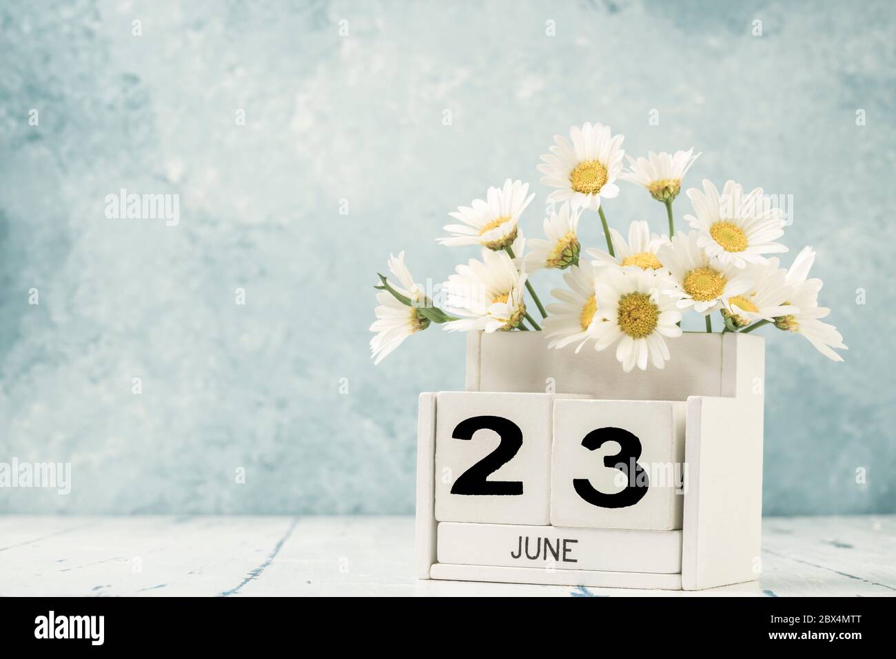 White cube calendar for june decorated with daisy flowers over blue ...