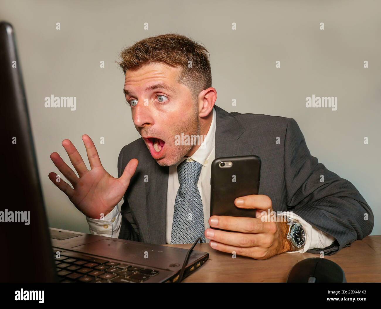 young stressed and surprised businessman in suit and tie working at ...