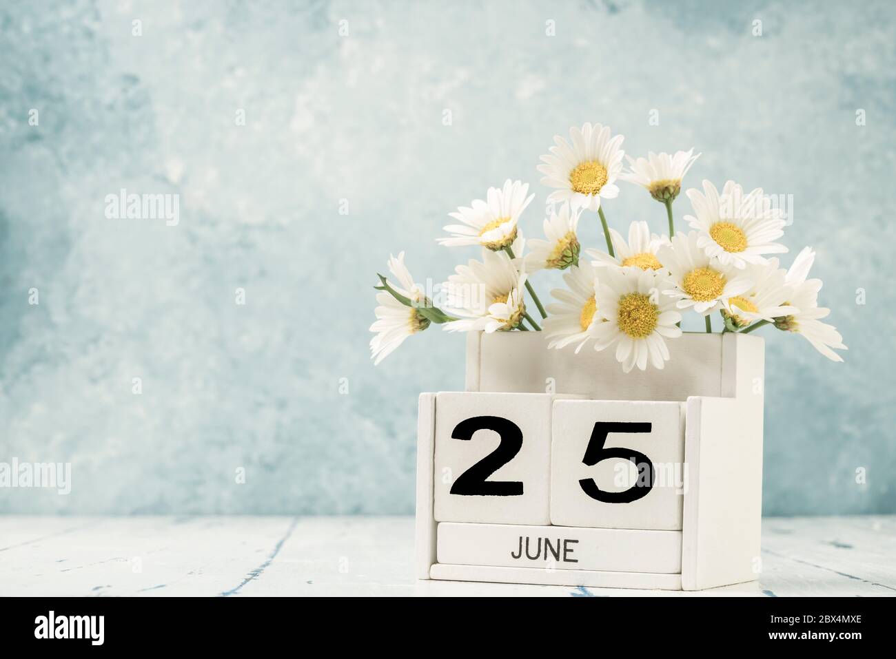 White cube calendar for june decorated with daisy flowers over blue ...