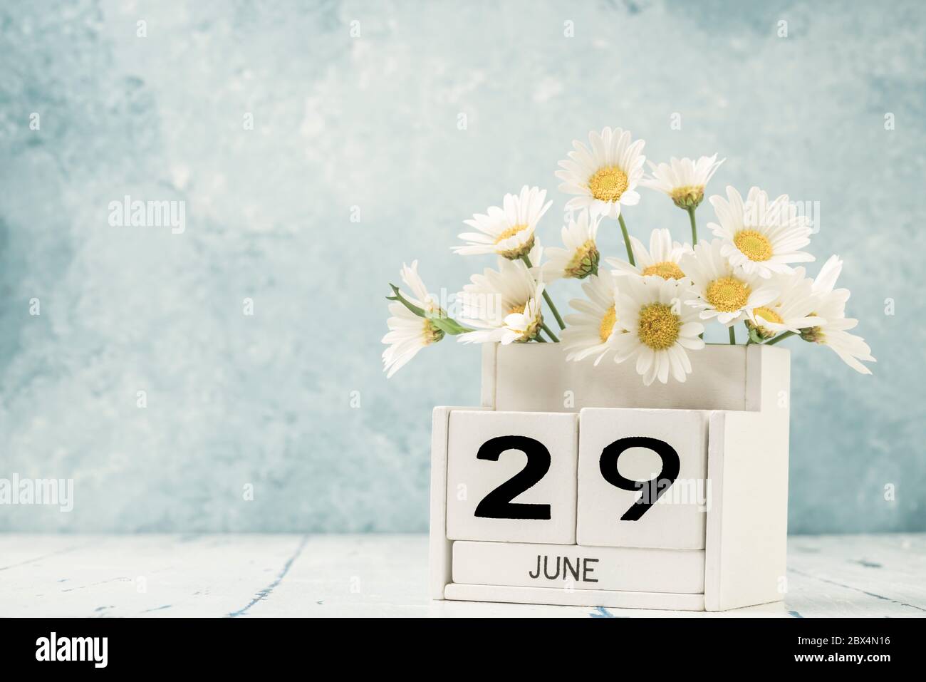 White cube calendar for june decorated with daisy flowers over blue ...