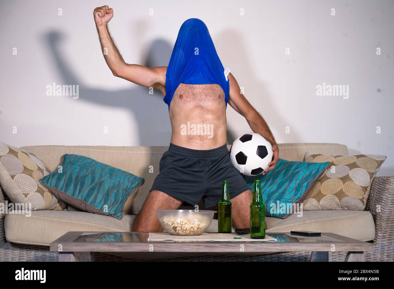 young attractive man happy and excited watching football match on TV ...