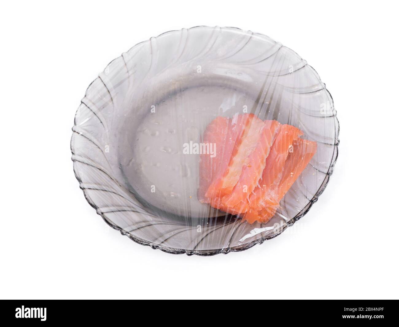 Piece of fish on plate under cling film isolated over white background ...