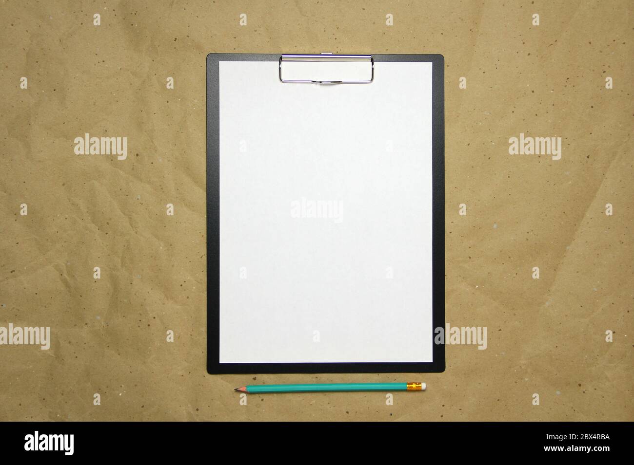 A tablet with a white sheet of A4 format with pencil on a beige craft ...
