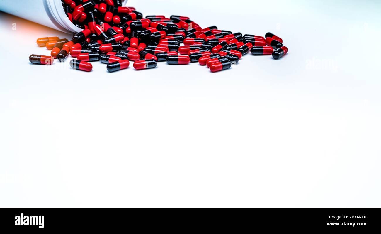 Red-black antibiotic capsule pills spread out of plastic drug bottle on ...