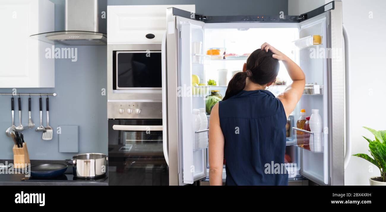 Hungry Women Looking At Food Inside Fridge Stock Photo - Alamy