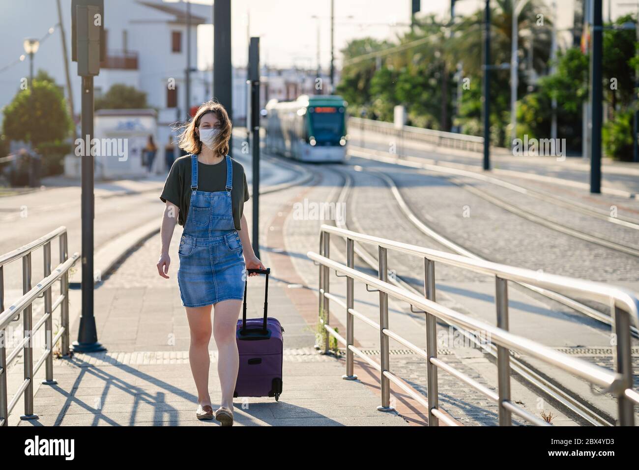 female traveler wearing protection mask arriving at the platform to ...