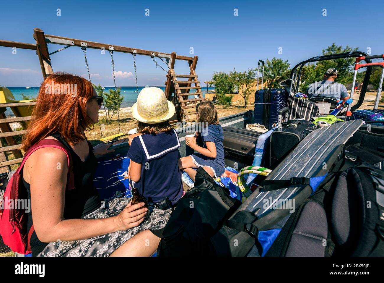Family riding a tractor trailer with suitcases and luggage. Family on ...