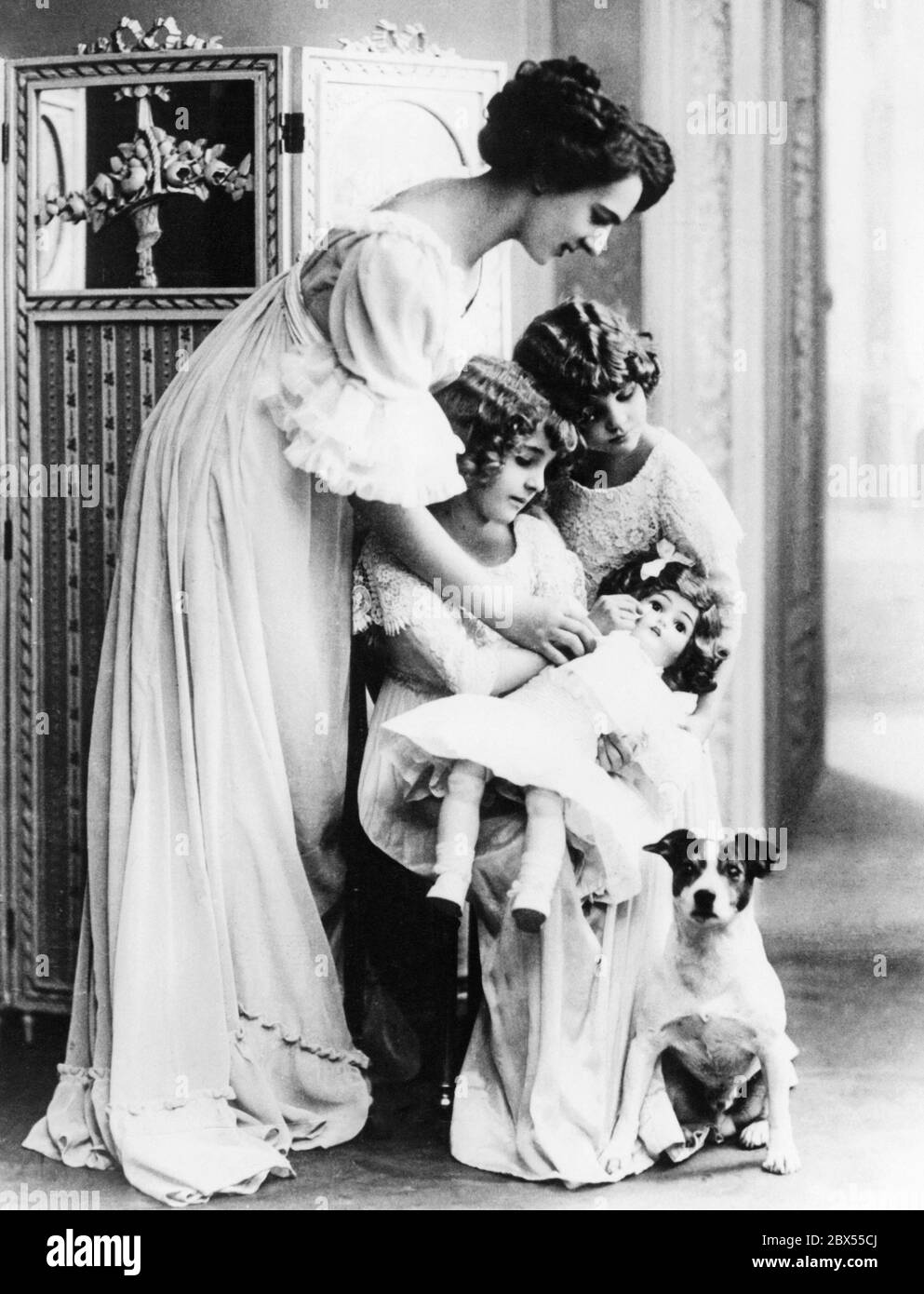 A mother teaches her two growing daughters how to handle babies using a ...