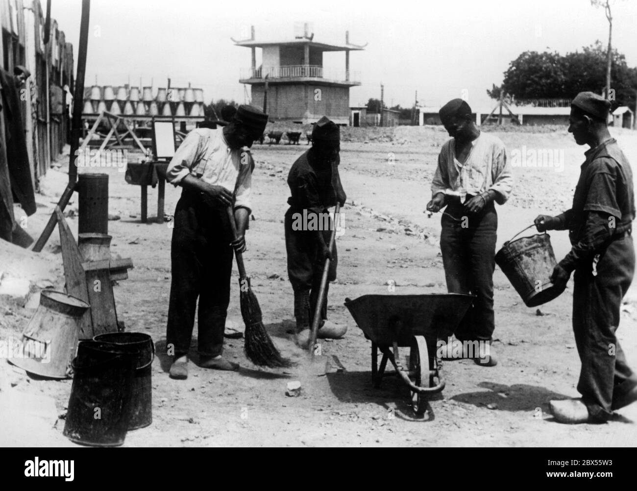 Camp inmates (light duty) clean up a prison camp in the occupied France ...