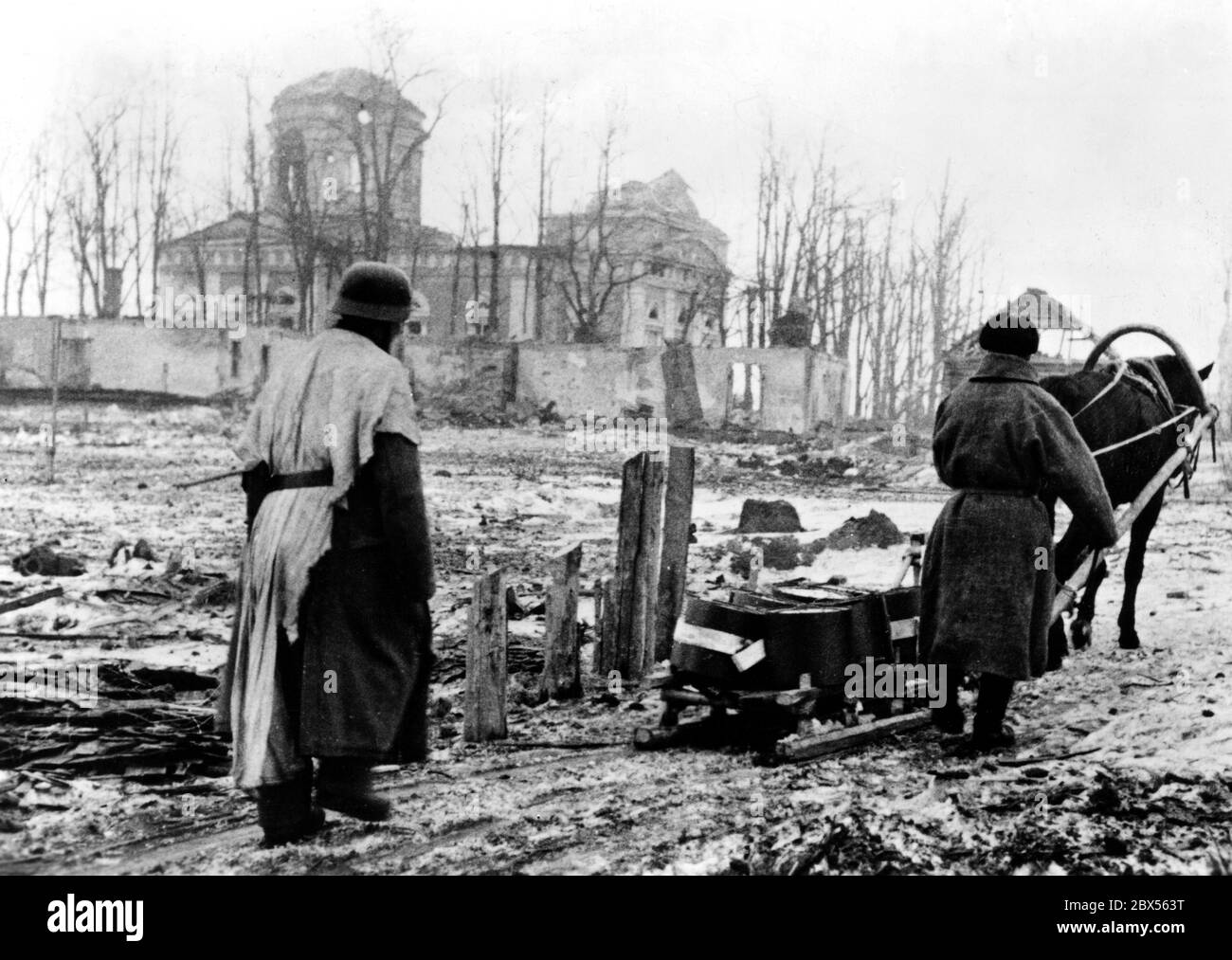 Two German soldiers pull a sledge with dropped provisions through the ...