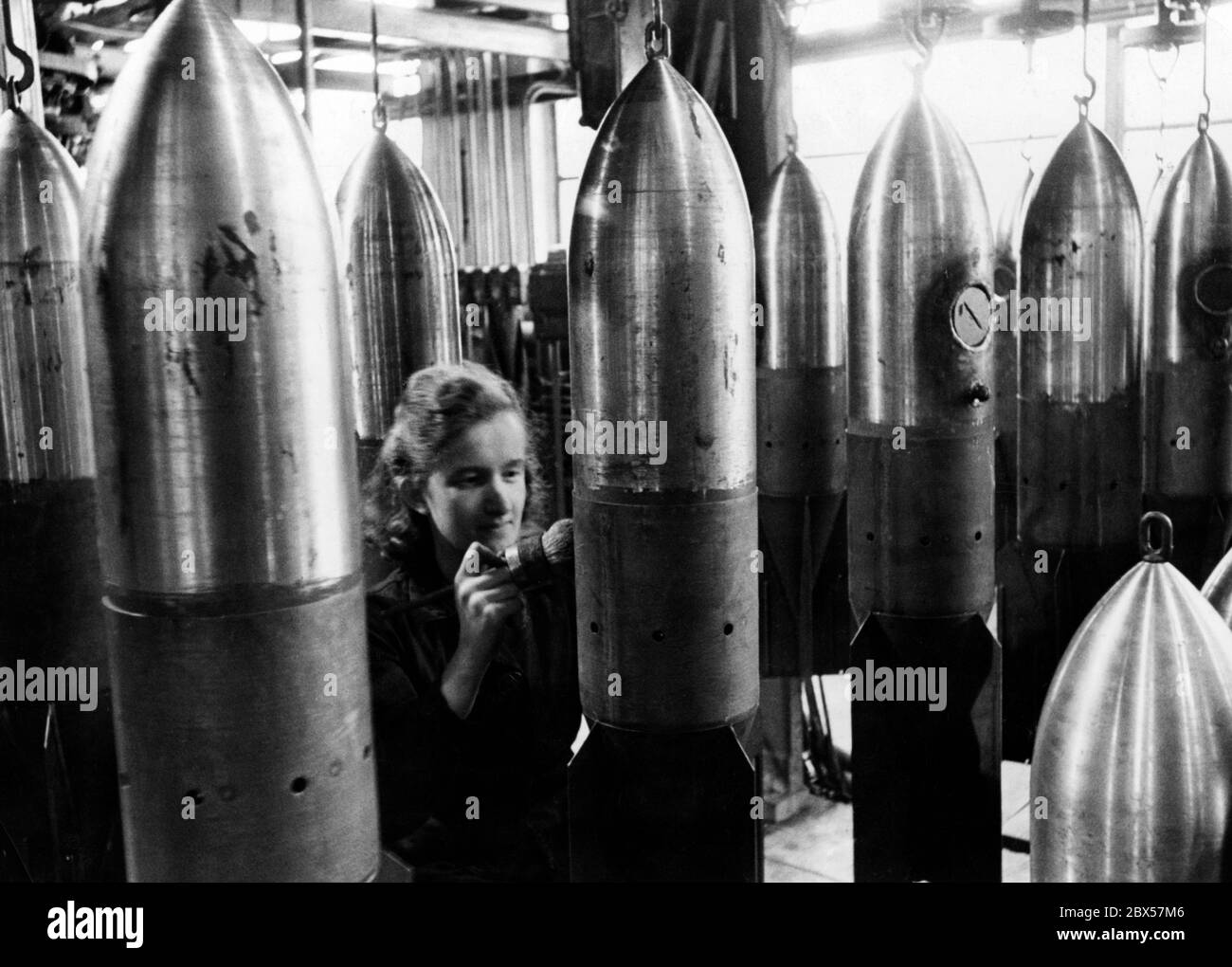 A worker in a "bomb forest" labels finished aircraft bombs with type ...